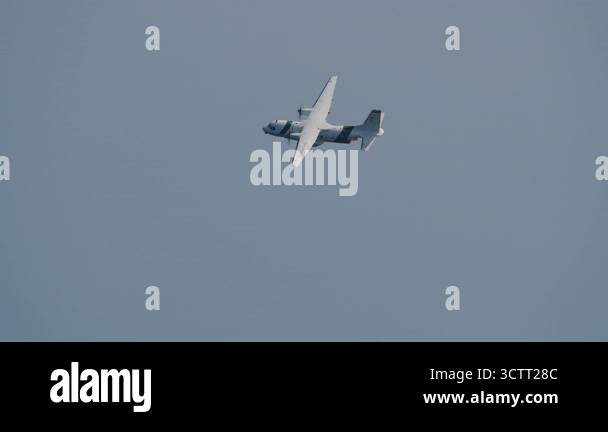 Military twin-engine propeller aircraft performing wide turn in mid-air ...
