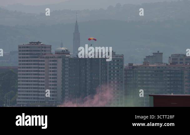 Solo parachutist with colorful canopy descending above high-rise ...
