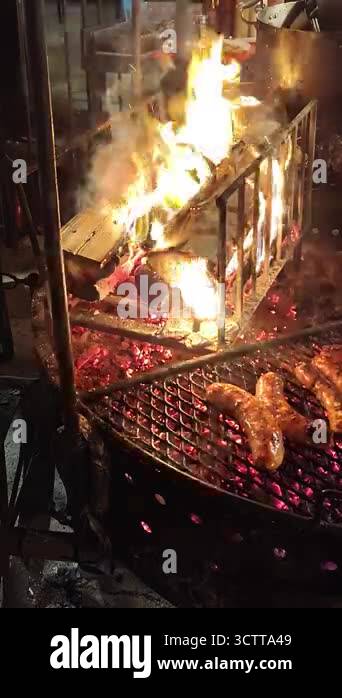 Vertical fixed shot video capturing sizzling flames over glowing embers ...