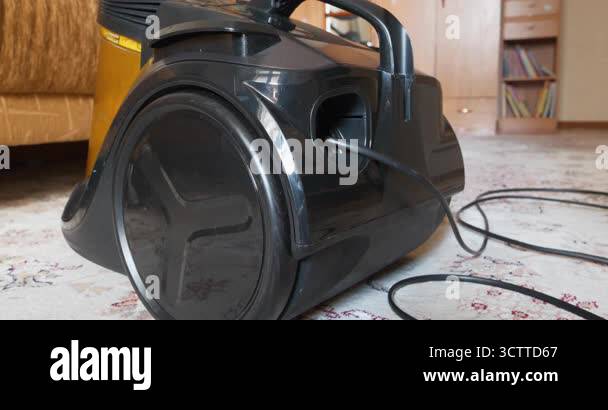 Vacuum cleaner cord retractor. Man presses button and electric cable ...