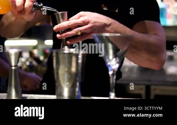 Bartender, hands close-up, preparing alcoholic cocktail, pouring into ...
