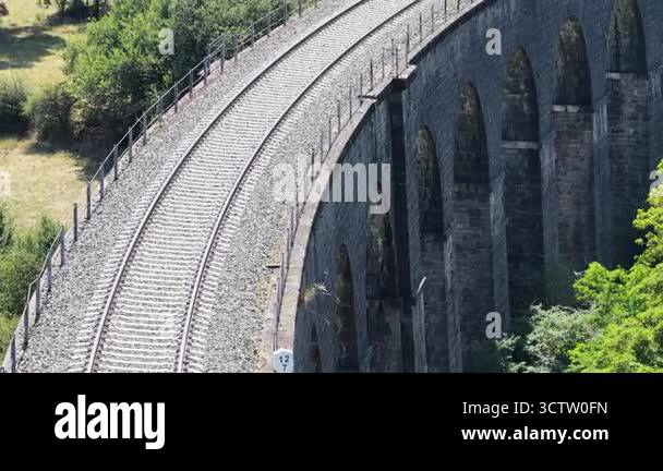 Stone railway bridge arching across a green valley, showing ...