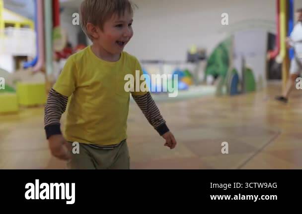 Cute little boy joyfully running and having fun in a colorful childrens ...