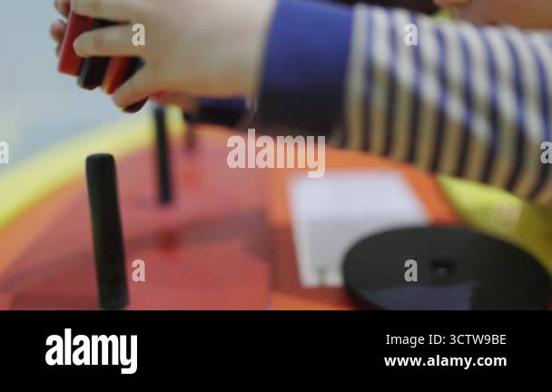 Child developing fine motor skills by stacking red and black rings on a ...