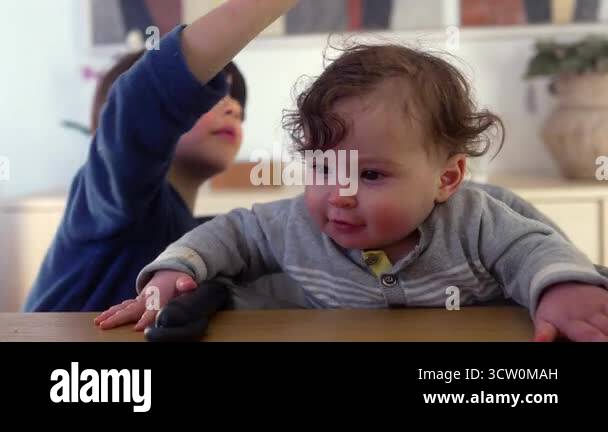 Older brother tousling baby sibling's hair with gentle playfulness at ...