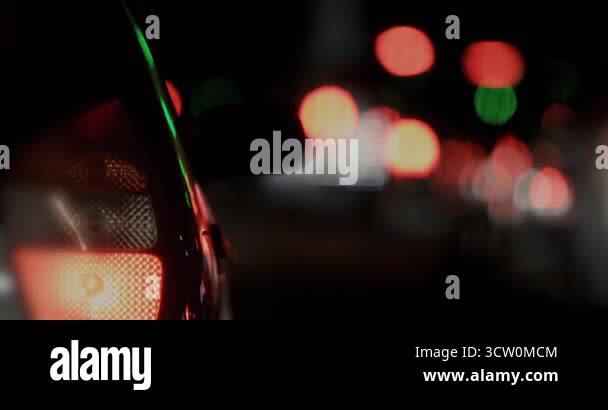 Rear of car with glowing red taillight, wide shot of night street with ...