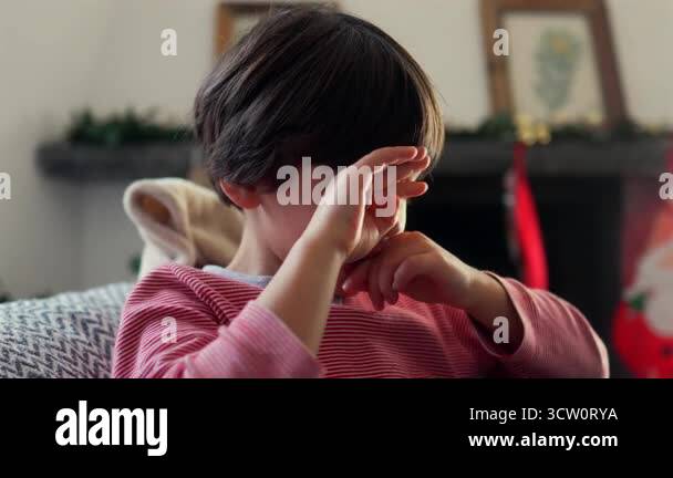 Young boy rubbing eyes while sitting on couch, looking tired and sleepy ...