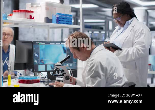 Employees team studying sample tray under the microscope for research ...