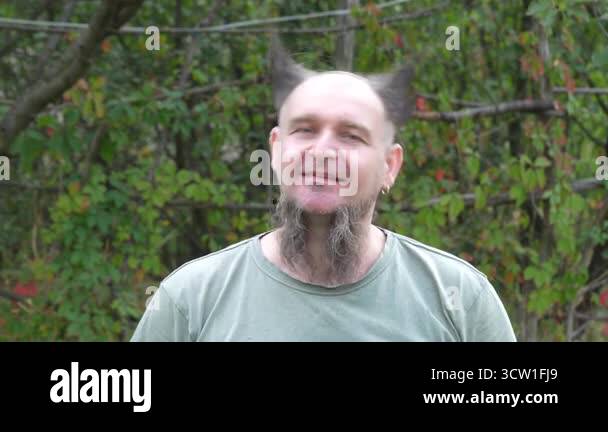 Funny bearded man with a bizarre hairstyle shakes his head in slow ...
