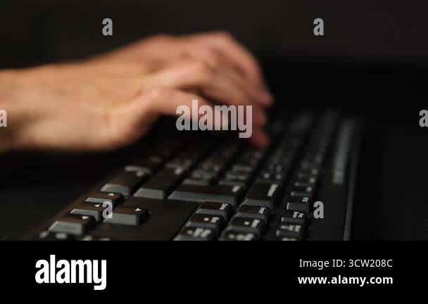 Close-up of hands typing on keyboard in dim light. Imperfect real-life ...