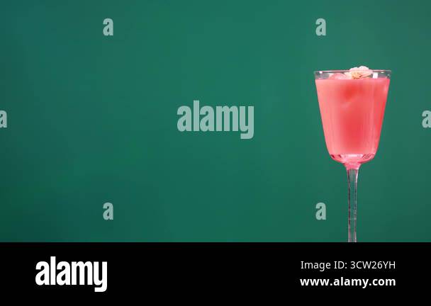 A pink cocktail in a glass against a green screen, showcasing vibrant ...