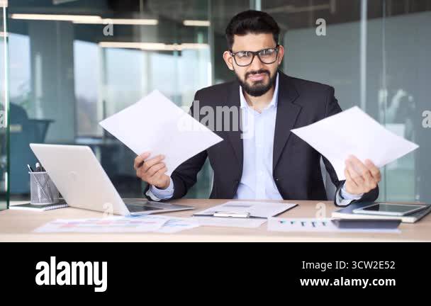 Confused puzzled businessman having difficulty with paperwork sitting ...