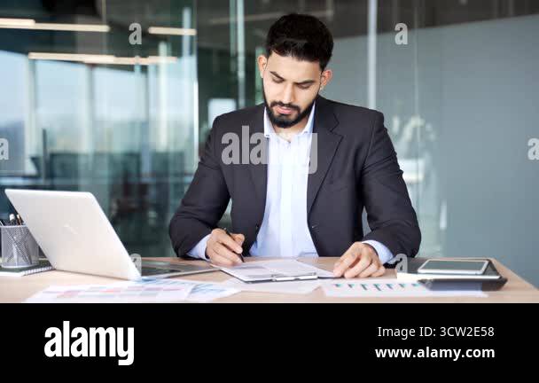 Businessman in formal suit signing documents sitting at a desk at ...