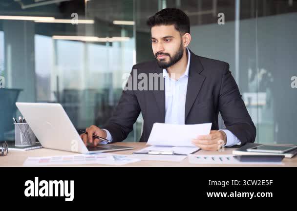 Portrait of serious male financier sitting at desk at workplace in ...