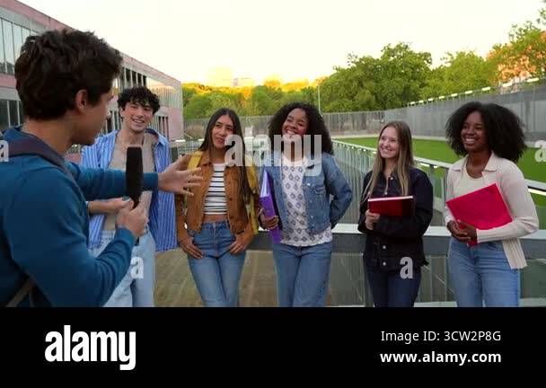 Male student journalist conducting a street interview with a group of ...