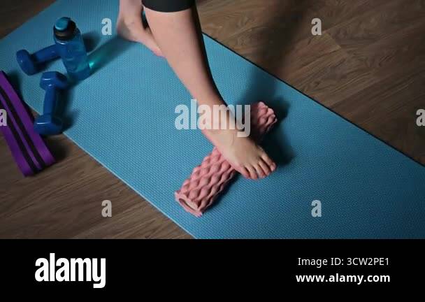 Female foot rolling massage fascia ball on yoga mat at home with ...