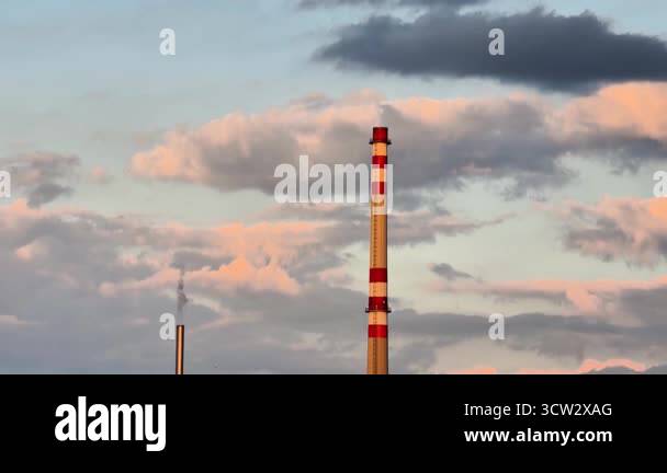 Stunning industrial chimneys are silhouetted against a vibrant sunset ...