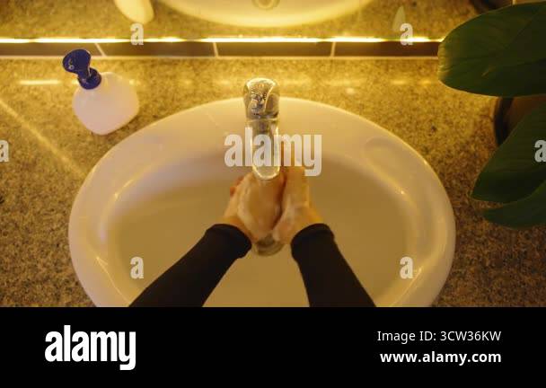 Overhead View of Person Washing Hands with Soap at Sink under Warm ...