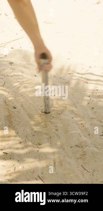 Vertical video. Woman Drawing a Heart Shape in the Sand Using a Stick ...