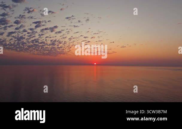 A tranquil drone shot of a stunning sunrise over calm sea waters, with ...