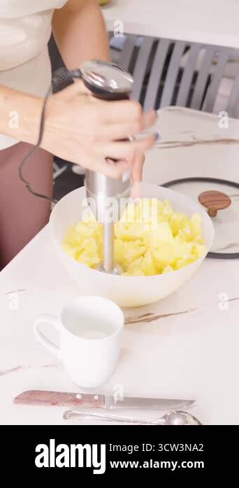 Vertical video. Woman Holding Hand Blender and Starting to Blend Boiled ...