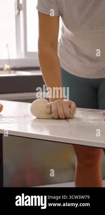 Vertical video. Woman Kneading Dough with Both Hands on White Table in ...