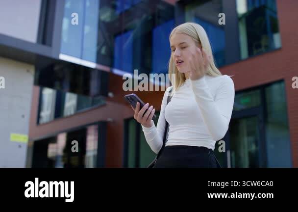 Concerned young woman holding smartphone and touching face with worried ...