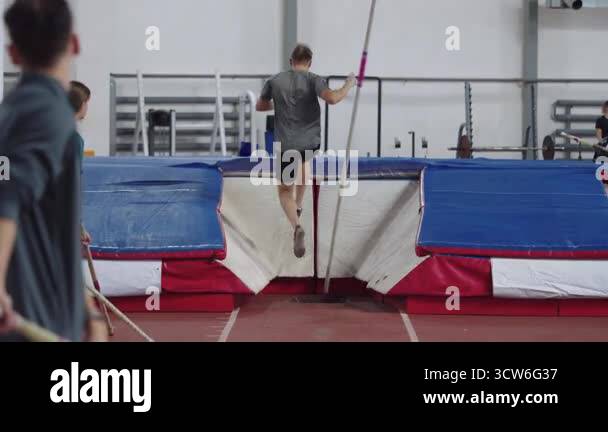 Male athlete jumping and doing a backflip on the landing mat during an ...