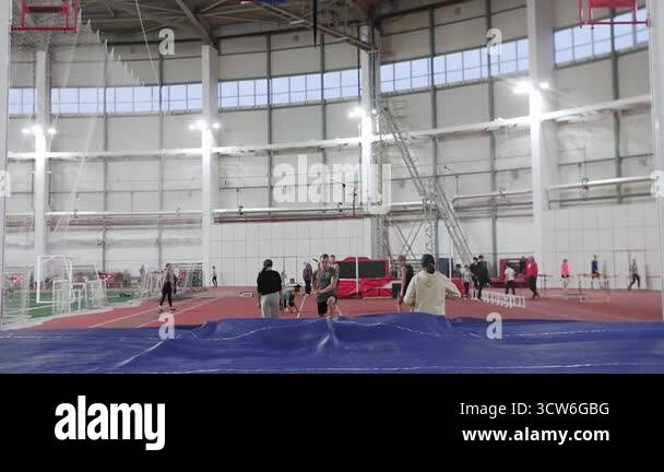 Athlete pole vaulting over a bar and landing safely on a mat during an ...