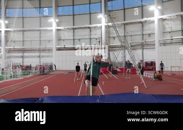 Young woman successfully completing a pole vault jump during an indoor ...