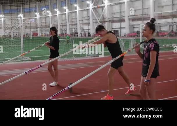 Teenage athletes holding poles preparing for a jump during track and ...
