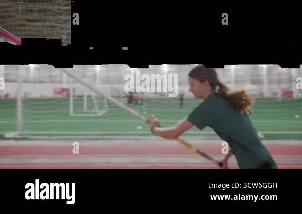 Young athletic woman performing a pole vault jump over the bar during ...