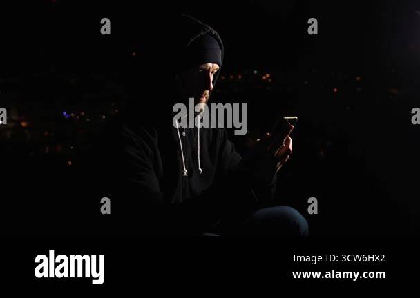 Man in hoodie sitting above Czech city and working on mobile phone at ...