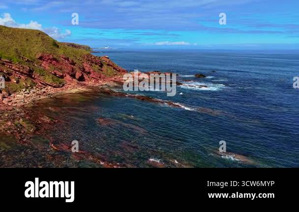 Waves lapping against red sandstone cliffs on North Sea coast in ...
