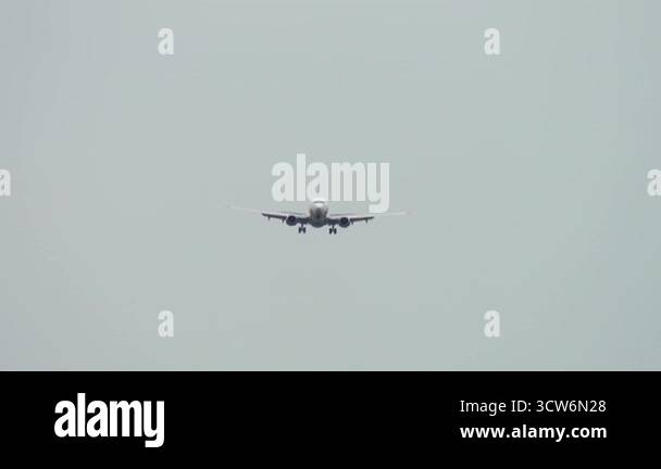 Jet airliner flying in windy cloudy weather with landing gear extended ...