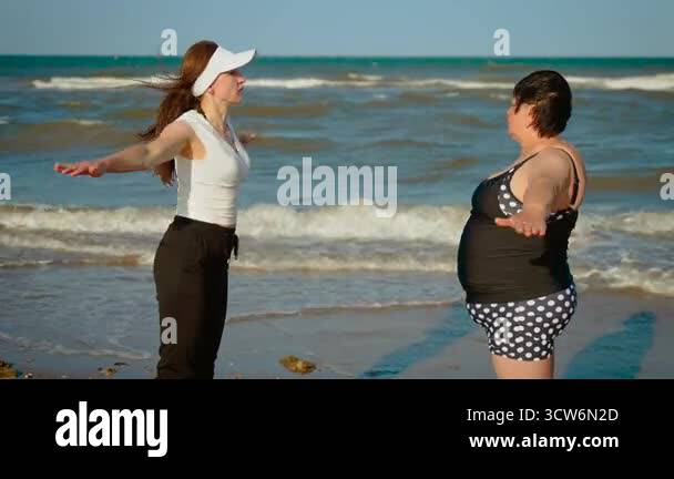 Ladies spreading arms on sea shore. Females stretching sideways on ...