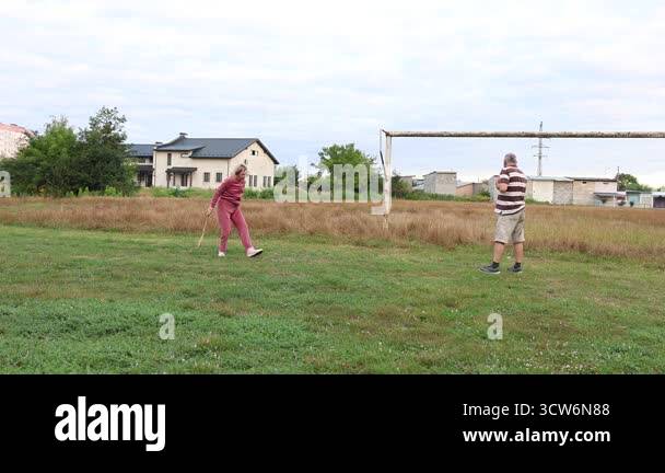 Two people playing badminton on a field near old football goalposts ...