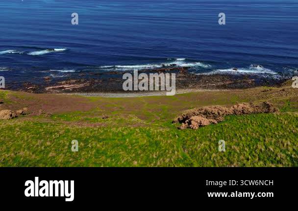 Waves rolling onto rocky shoreline along deep blue ocean. Sea meeting ...