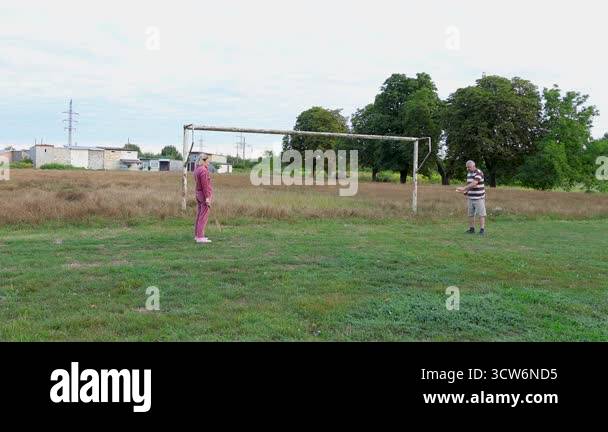 Two people playing badminton on a field near old football goalposts ...