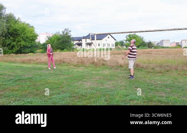 Two people playing badminton on a field near old football goalposts ...