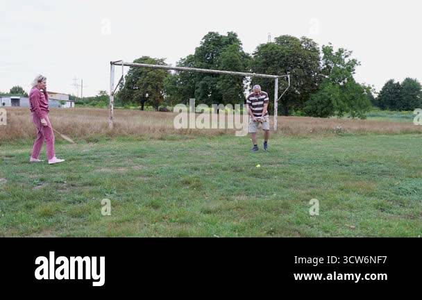 Two people playing badminton on a field near old football goalposts ...