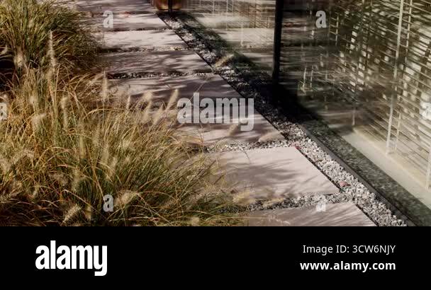 Modern Pathway by Glass Wall. A serene walkway with stepping stones ...