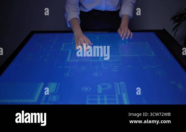 Behind a large monitor instead of a desk, a woman actively uses an interactive diagram on the ...