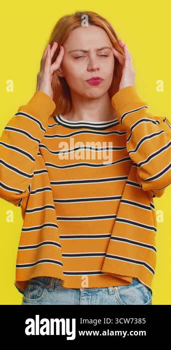 Displeased exhausted Caucasian blonde woman in blouse rubbing temples ...