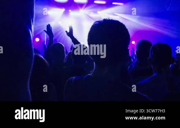 Energetic audience at live concert performance. Fans raising hands ...