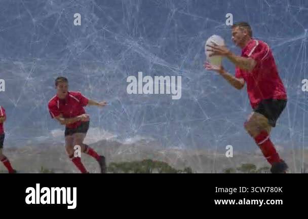 Red player catching pass in rugby on grass charging forward for attack ...