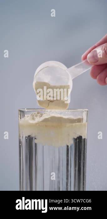 protein powder spills in glass of water from measure scoop. whey sports ...