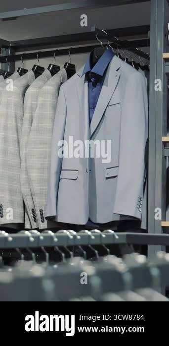 Display of formal shirts and suits in a retail clothing store. A neatly ...