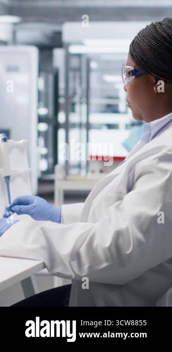 Vertical Video African american researcher examining Petri dish in a ...