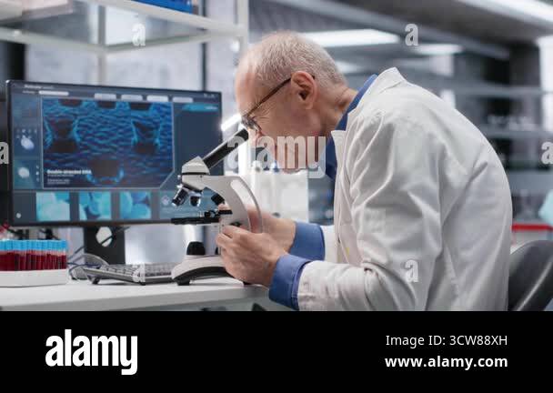 Laboratory with old male scientist observing specimen under microscope ...